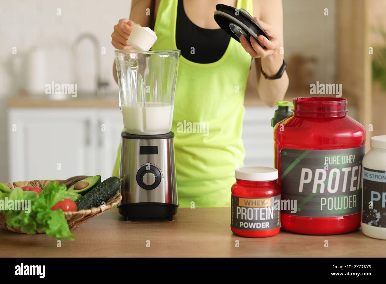 Sporty young woman making protein shake in blender at home, closeup ...