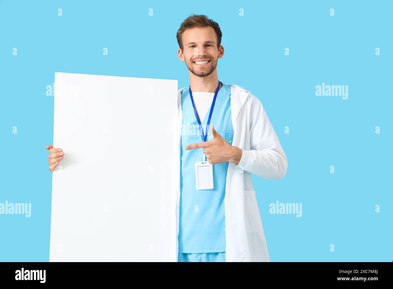 Male medical intern pointing at blank poster on blue background Stock ...