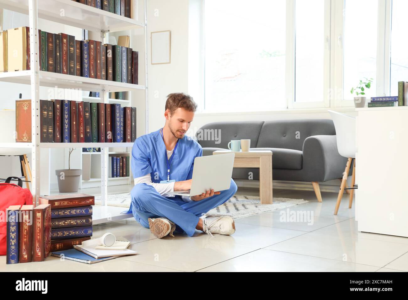 Male medical intern studying with laptop in library Stock Photo - Alamy