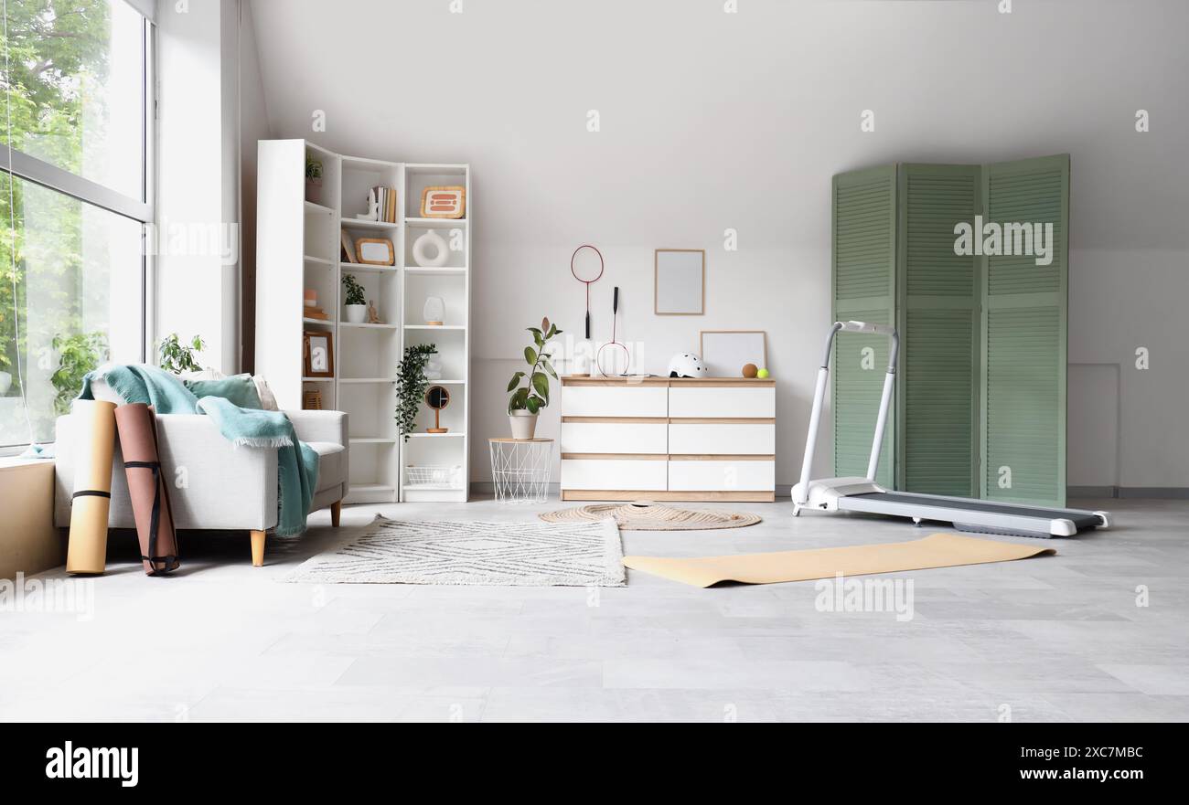 Interior of gym with sports equipment, sofa and drawers Stock Photo - Alamy