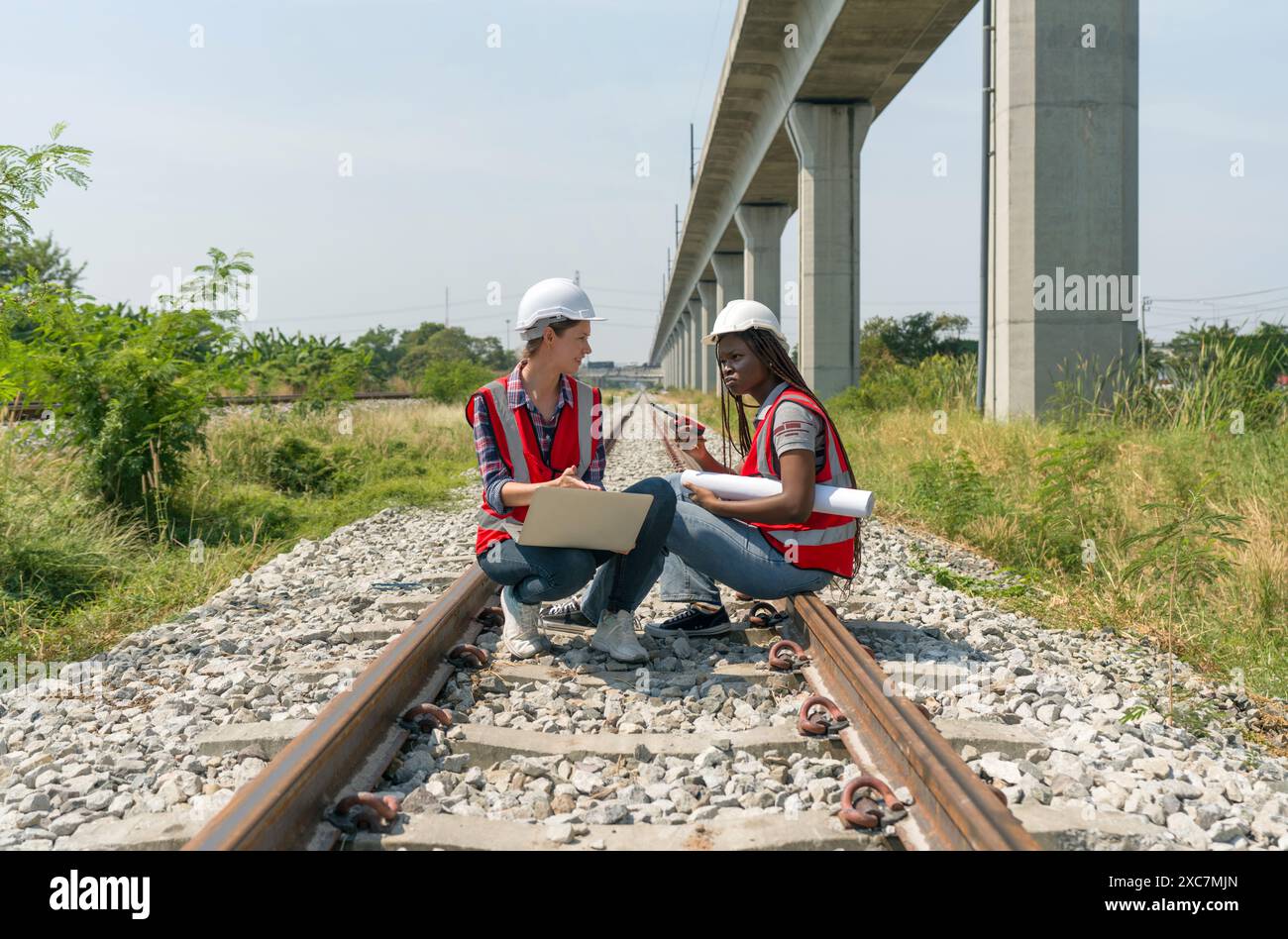 Two engineer with safety helmet and high-visibility vest reviewing work ...