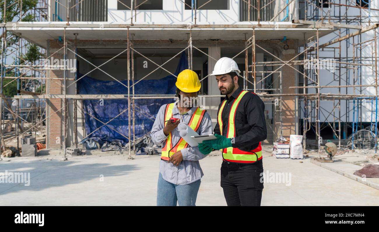 Two construction workers checking work schedule on tablet computer ...