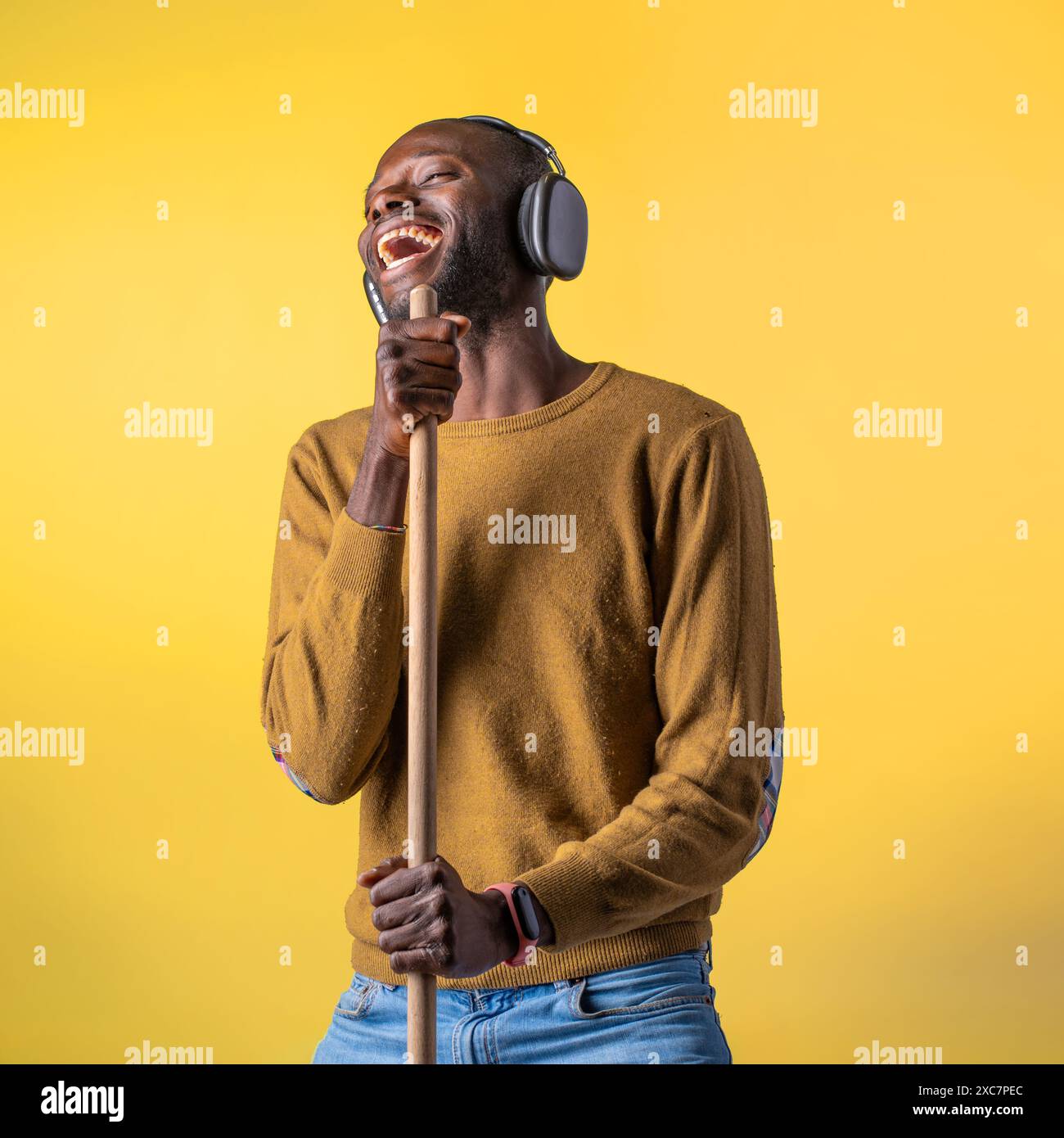 Joyful young African American man singing with headphones, using a ...