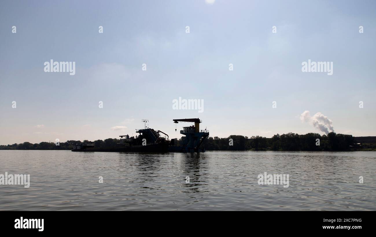 A river barge ready for sand loading poised next to the anchored ...