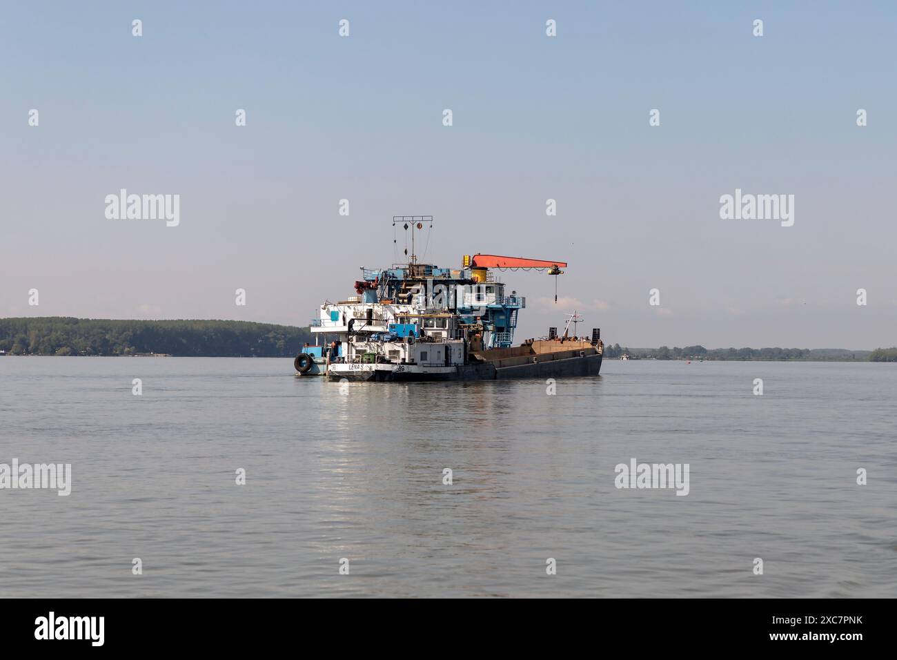 A river barge ready for sand loading poised next to the anchored ...