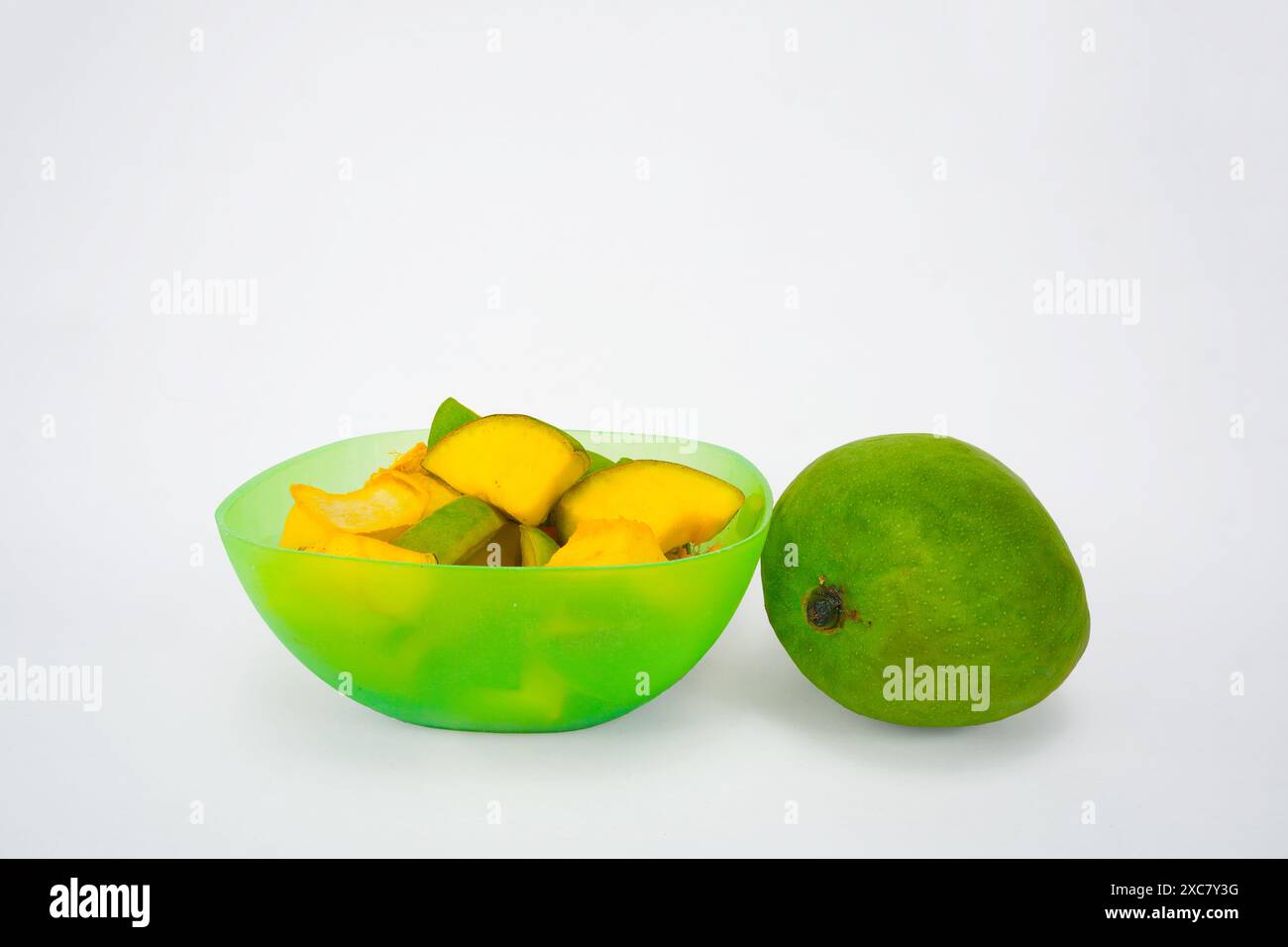 Slices of mangos in green bowl with one mango, isolated on white ...