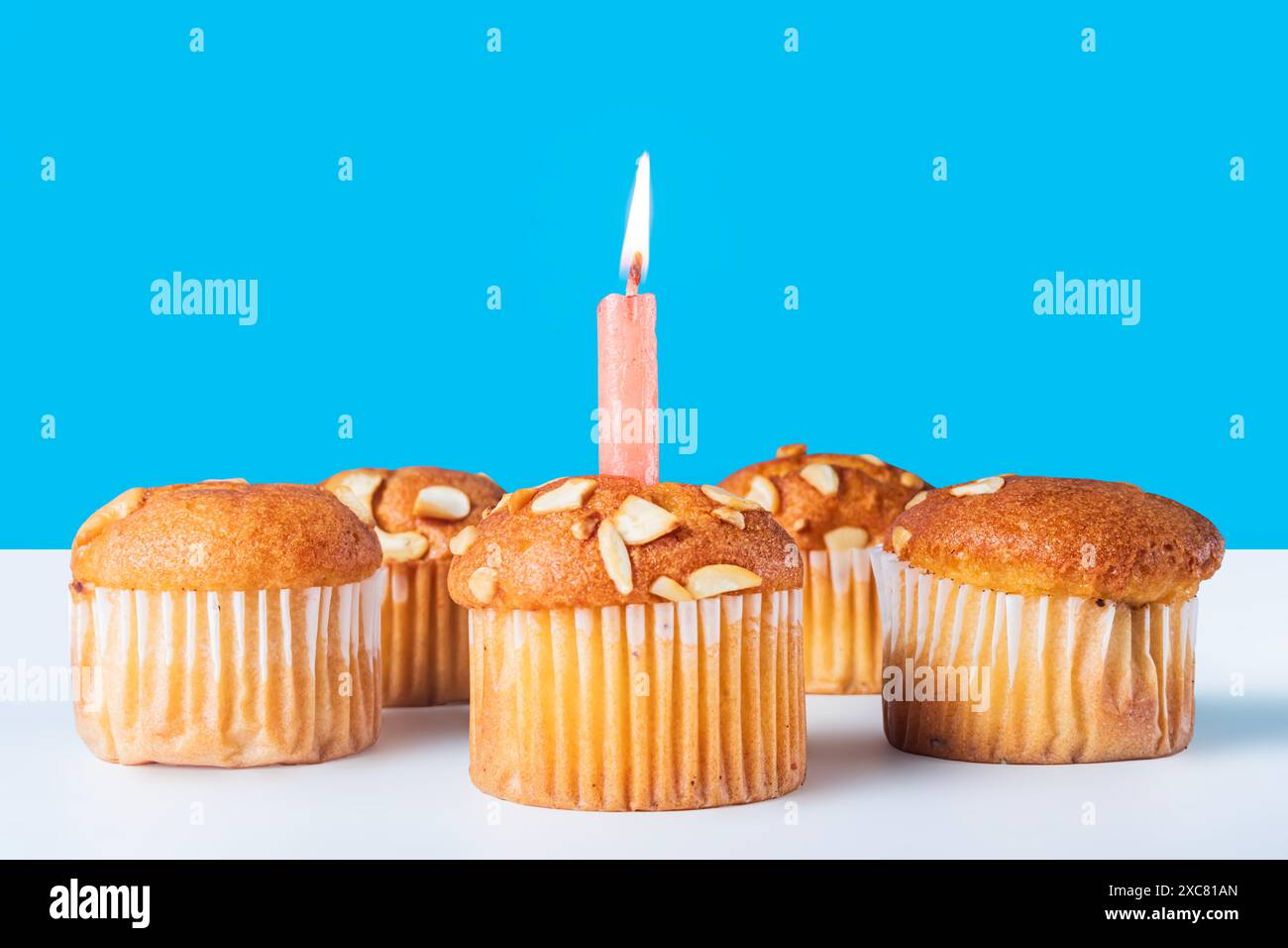 Birthday cupcakes with single lit candle on blue background Stock Photo - Alamy