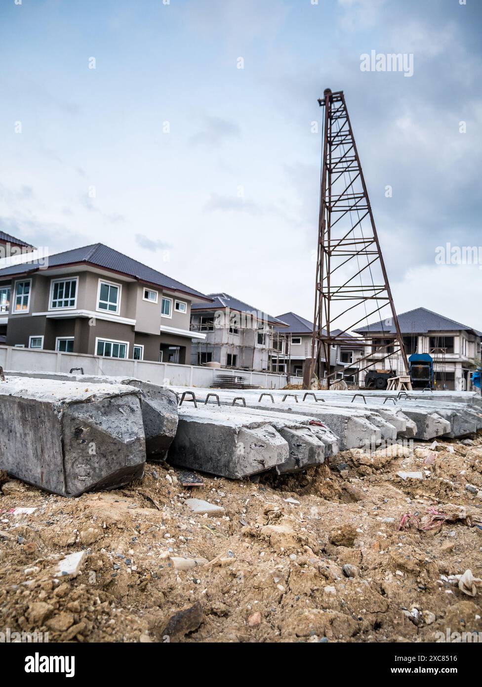 house building at construction site with pile driver and precast ...