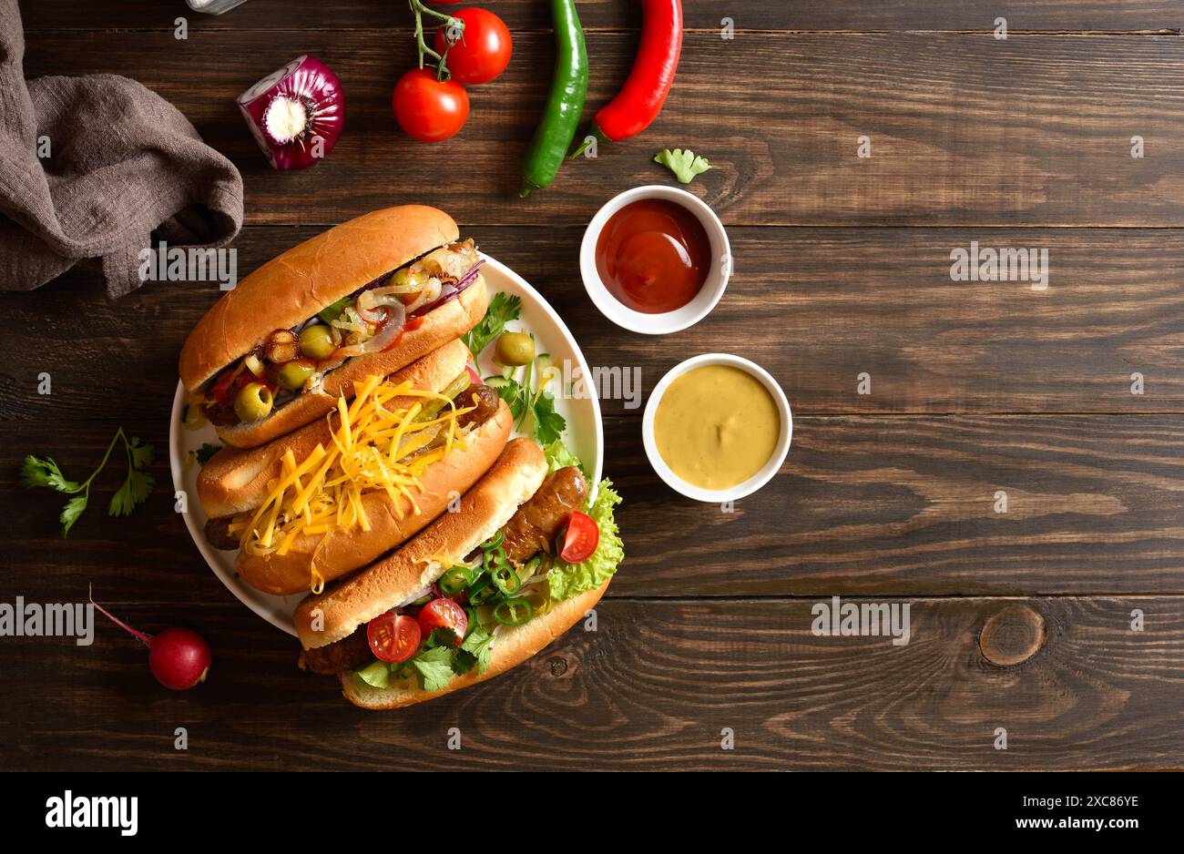 Hot dogs with different toppings on white plate on wooden background ...