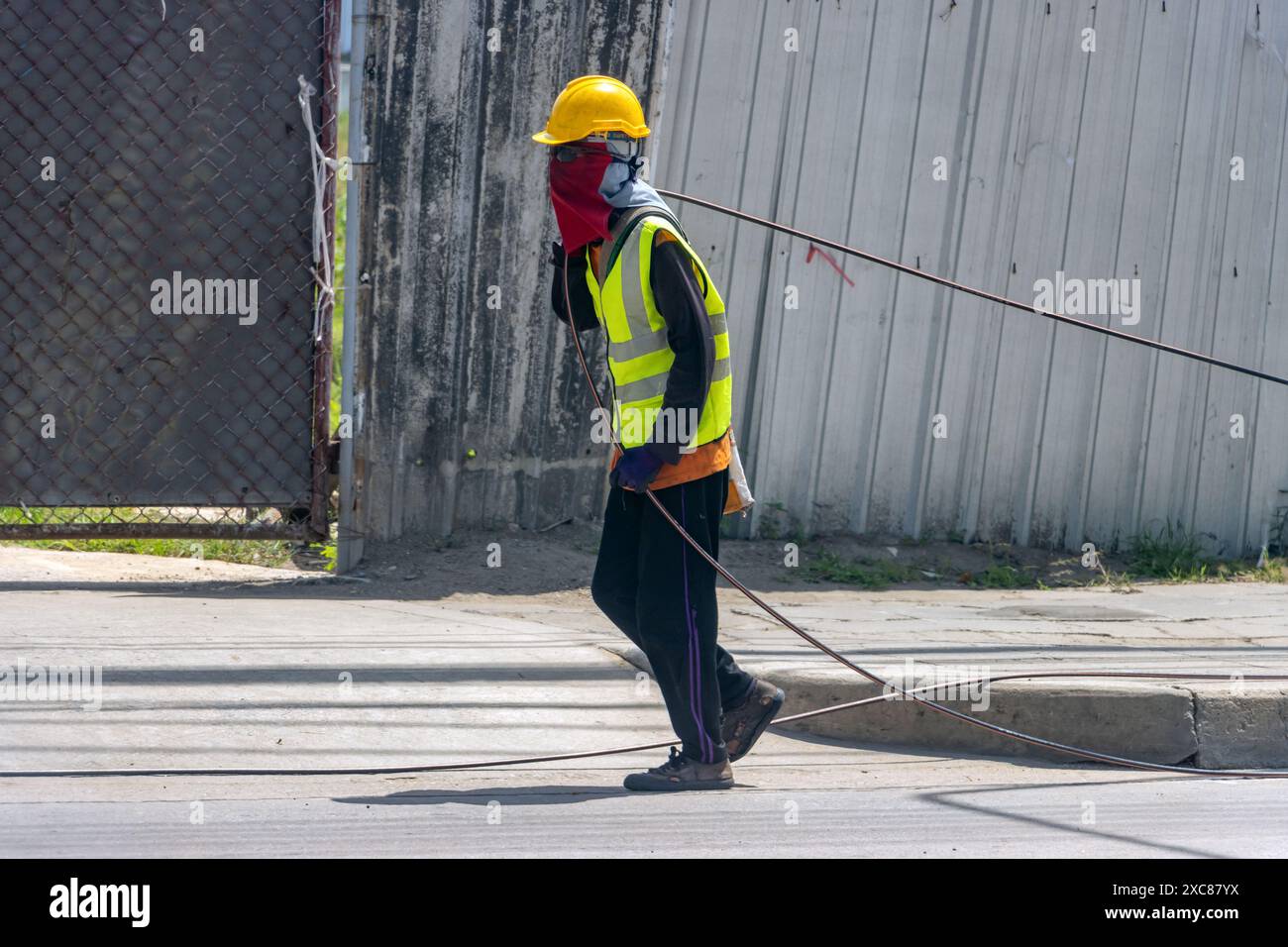 A worker pulls an electric cable on the street Stock Photo - Alamy