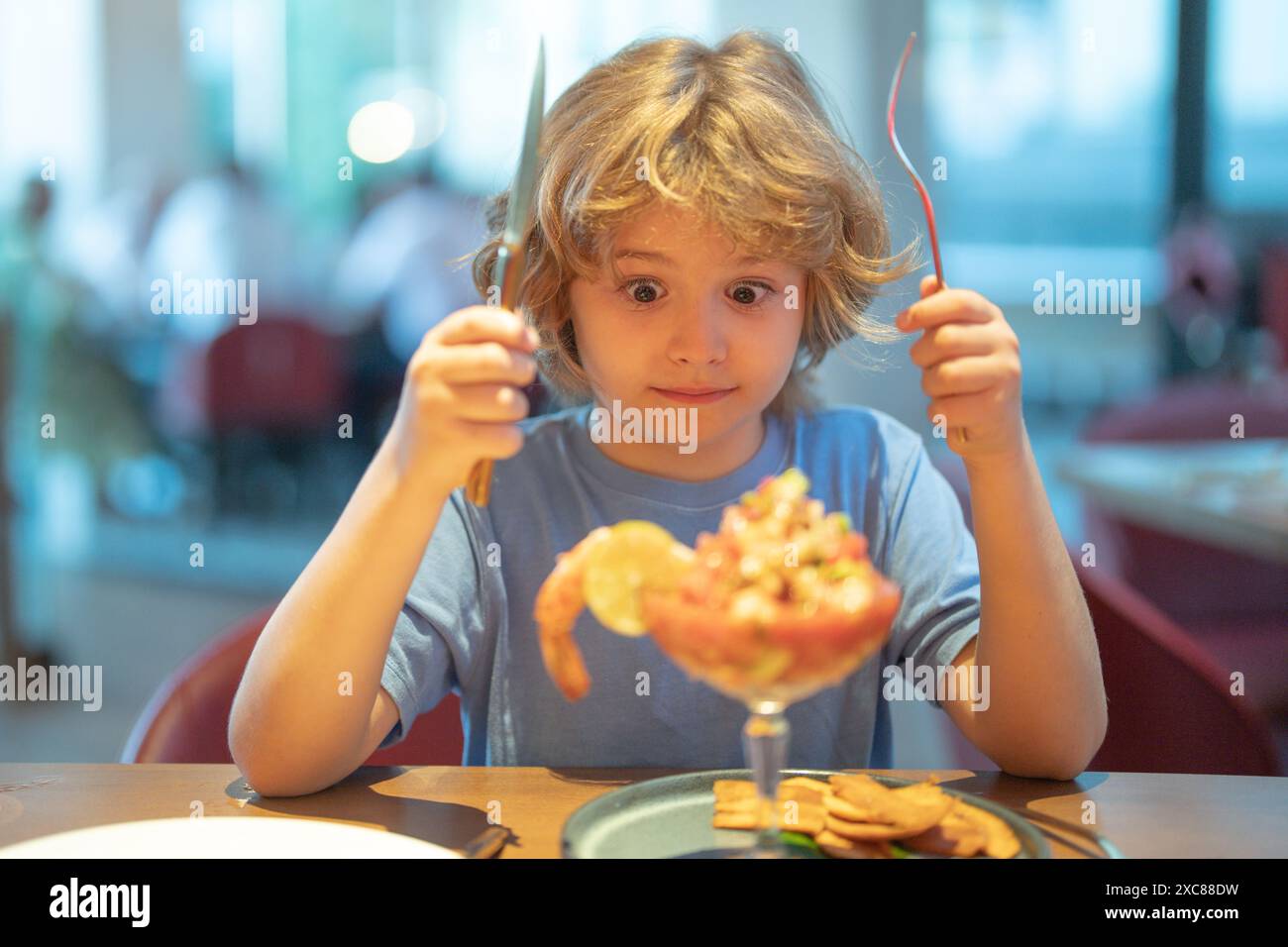 Funny surprised Little boy eating seafood in cafe. Kid eat Food fish ...