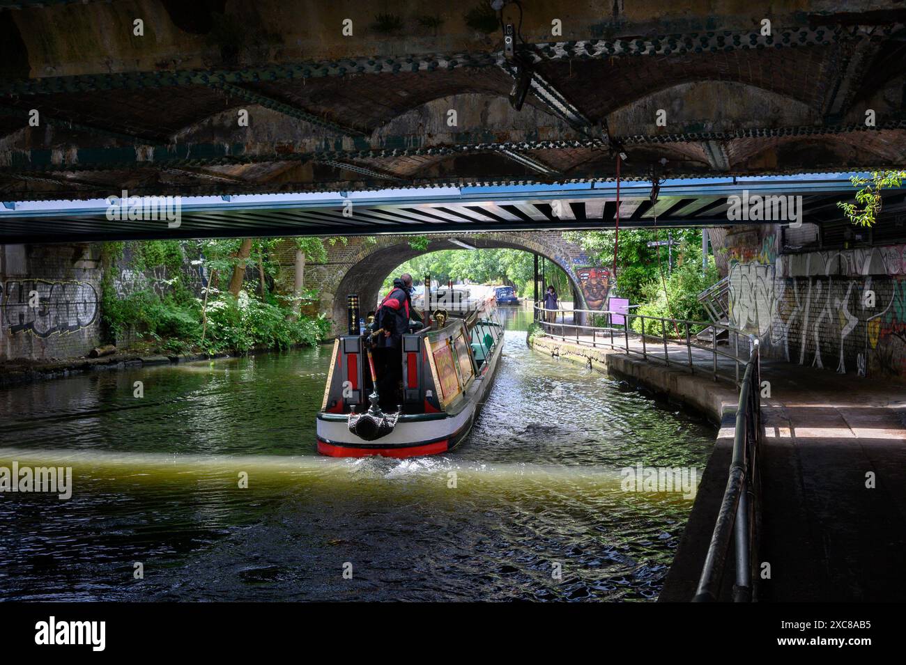 London, UK. Barge passing under a bridge near Camden Lock on the ...