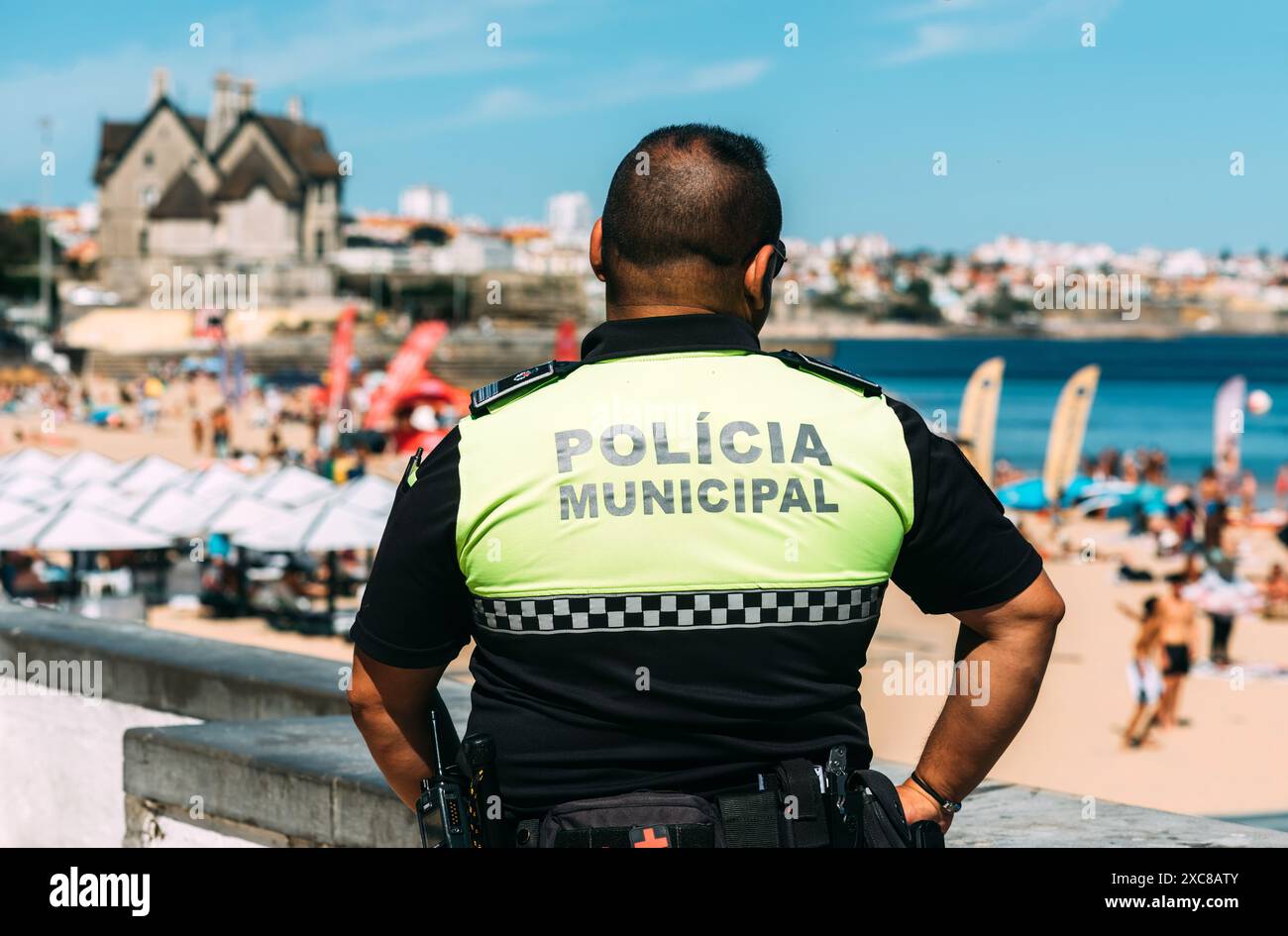 A Cascais Municipal Police officer stands on a beach patrol, facing the ...
