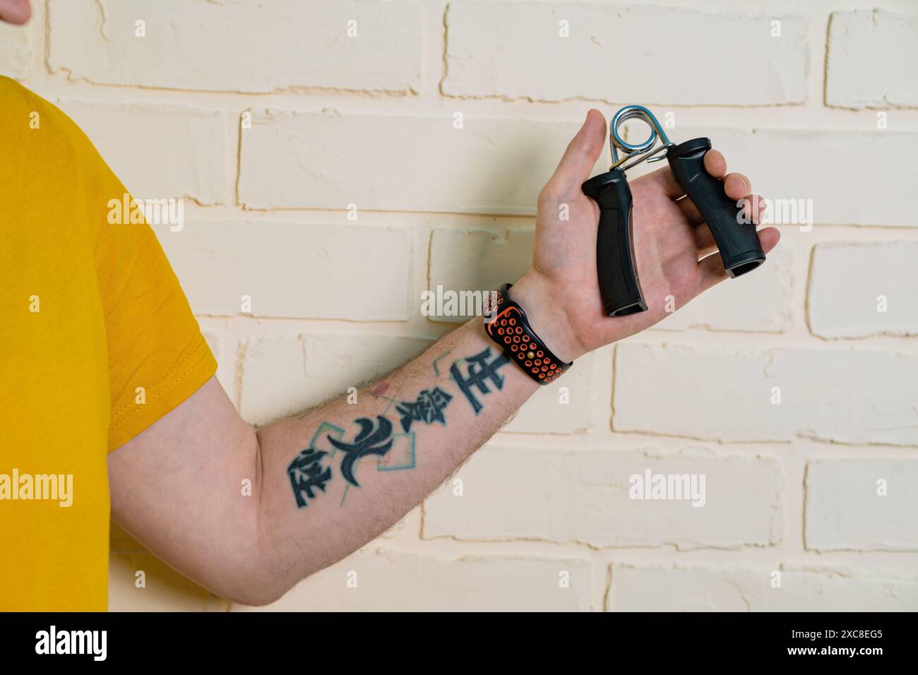 A Mans Arm With A Tattoo Flexes His Hand With A Gripping Device In ...