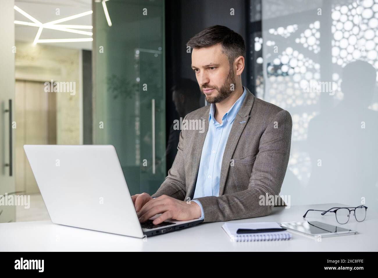 Professional businessman working on a laptop in a modern office setting ...
