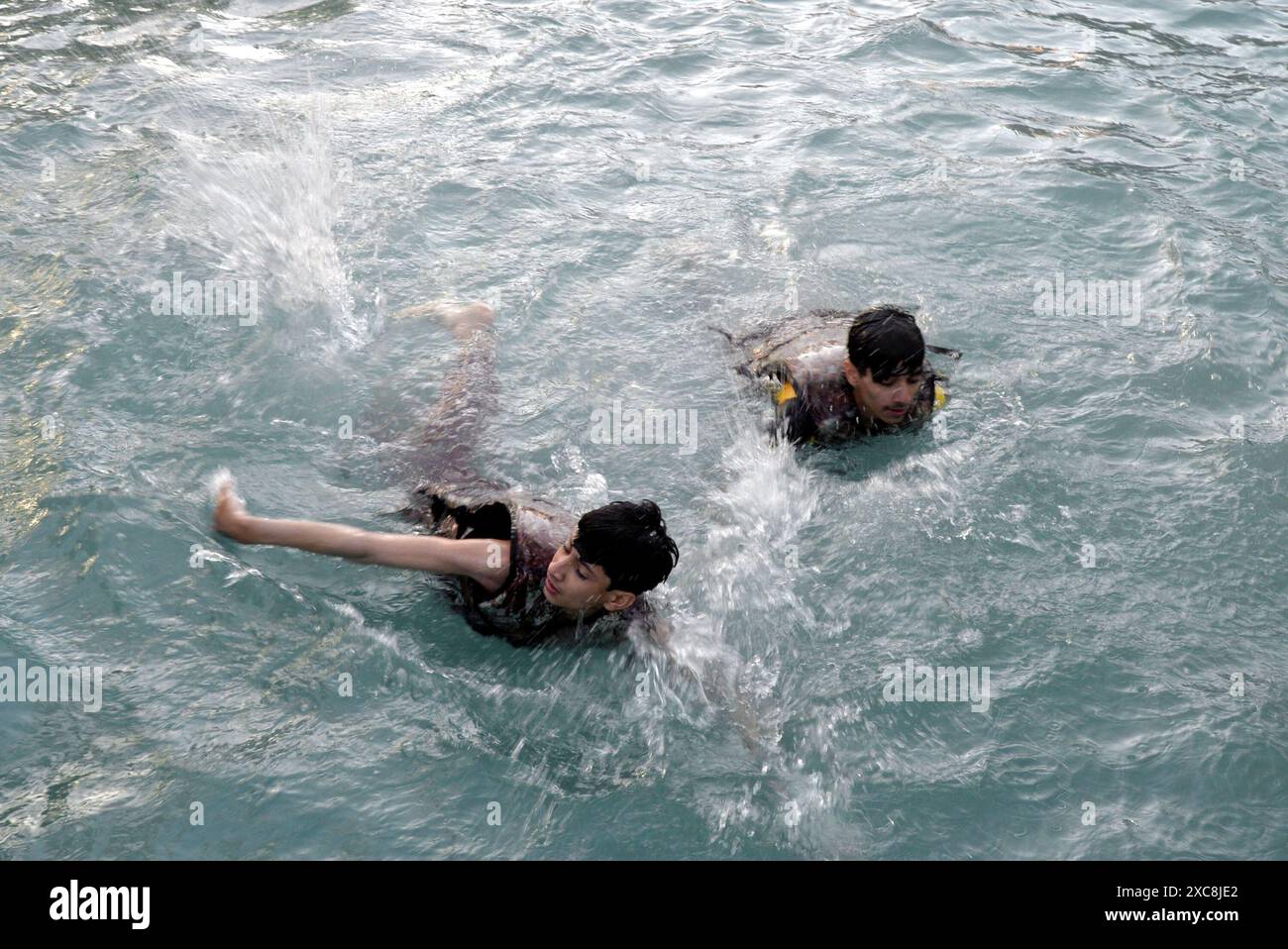 Peshawar. 15th June, 2024. People swim to escape the summer heat in ...