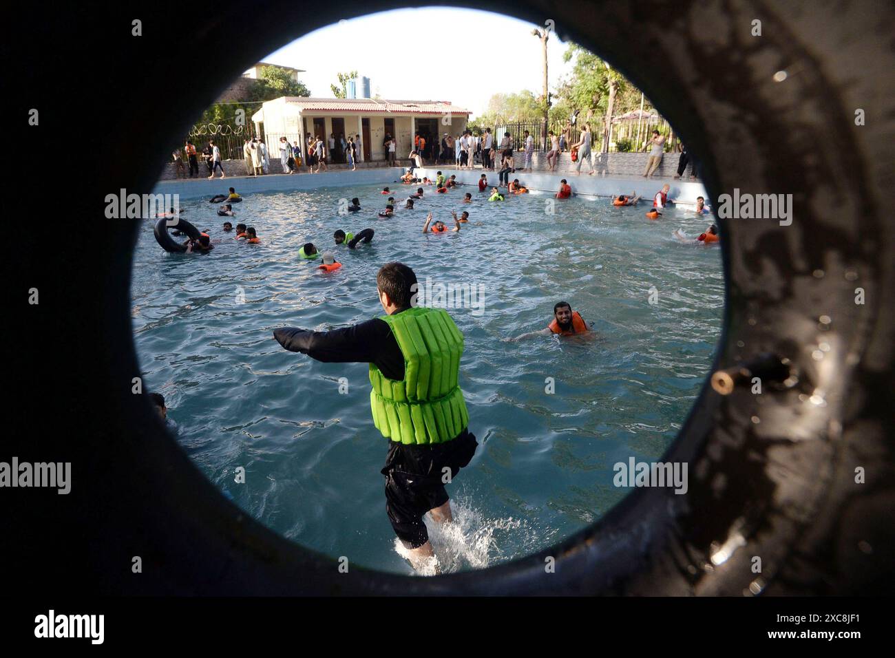 Peshawar. 15th June, 2024. People swim to escape the summer heat in ...