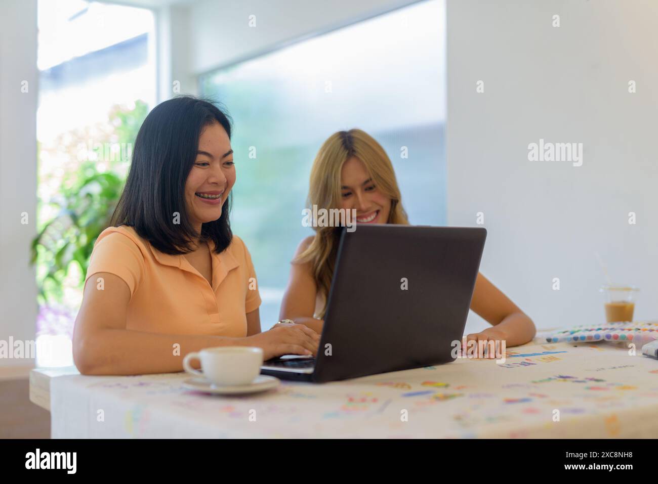 Two woman sitting in coffee shop using laptop computer together while ...