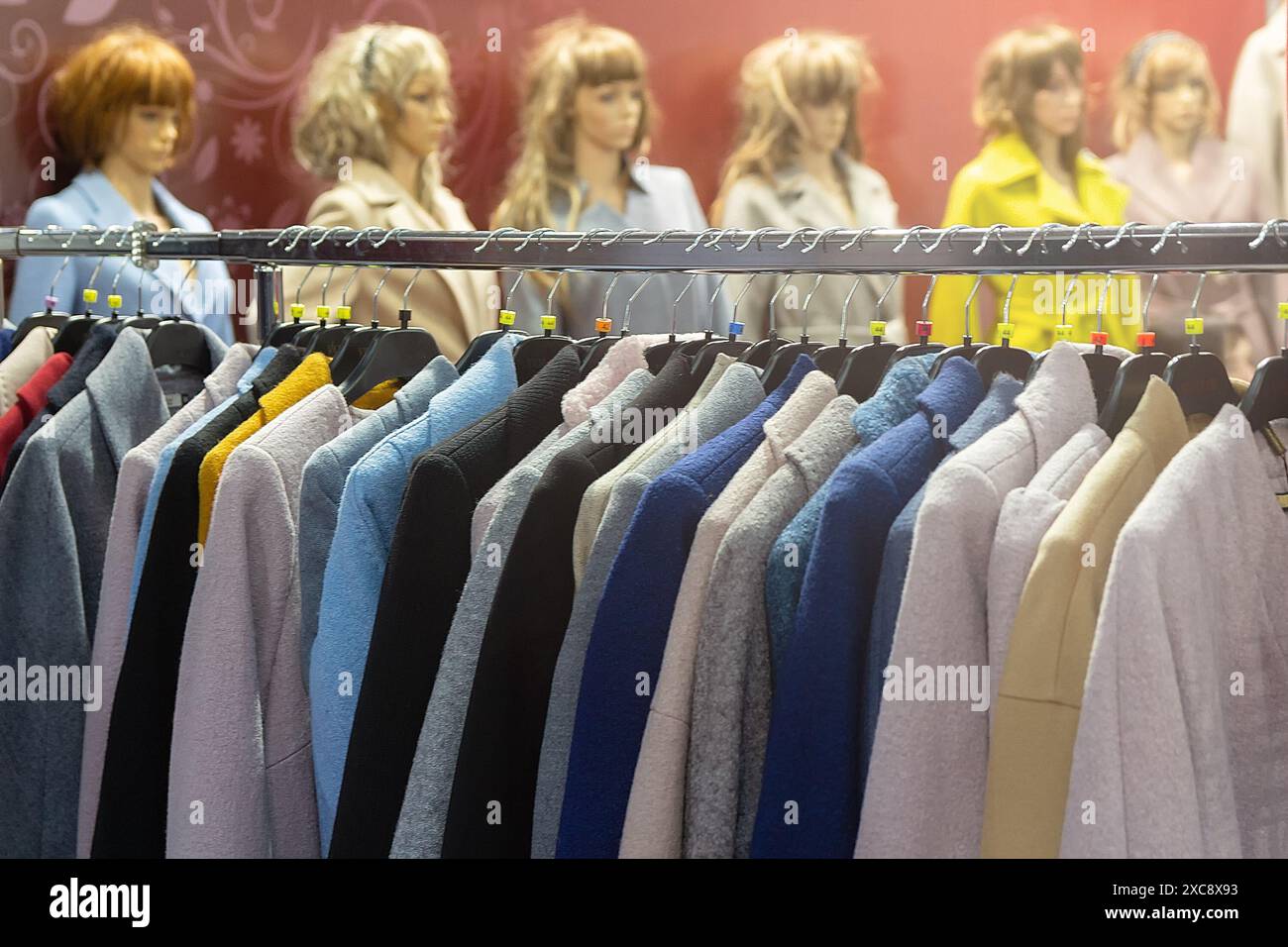 Multi-colored women's coats on hangers and mannequins in the store ...