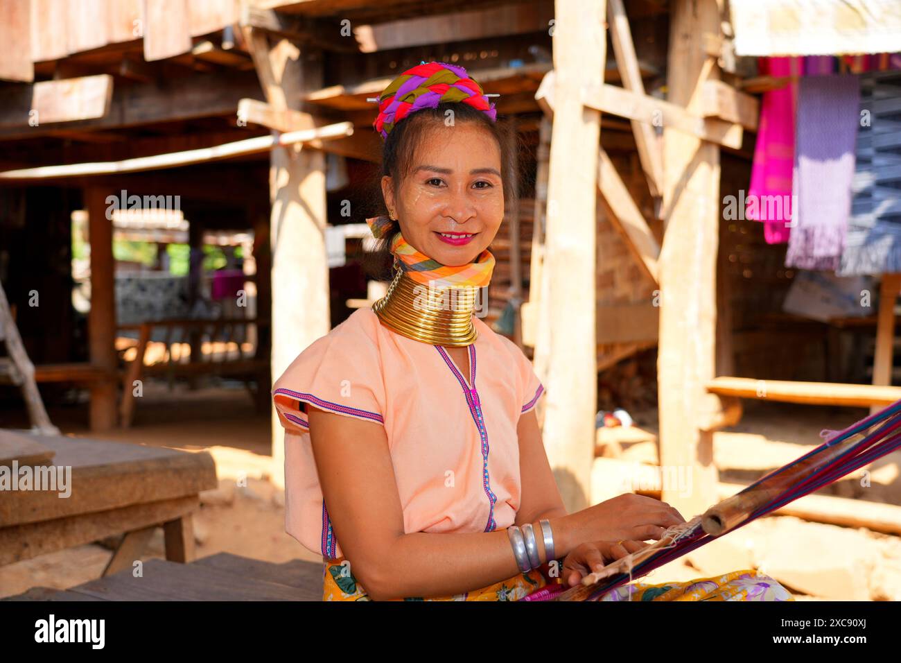 Kayan long-neck woman weaving in the Huay Pu Keng ethnic village while wearing brass neck rings ...