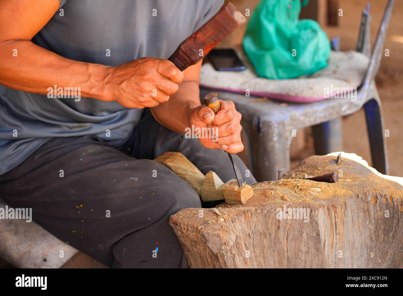 Kayan refugee craftsman chiseling wood to make a small statue in the ...