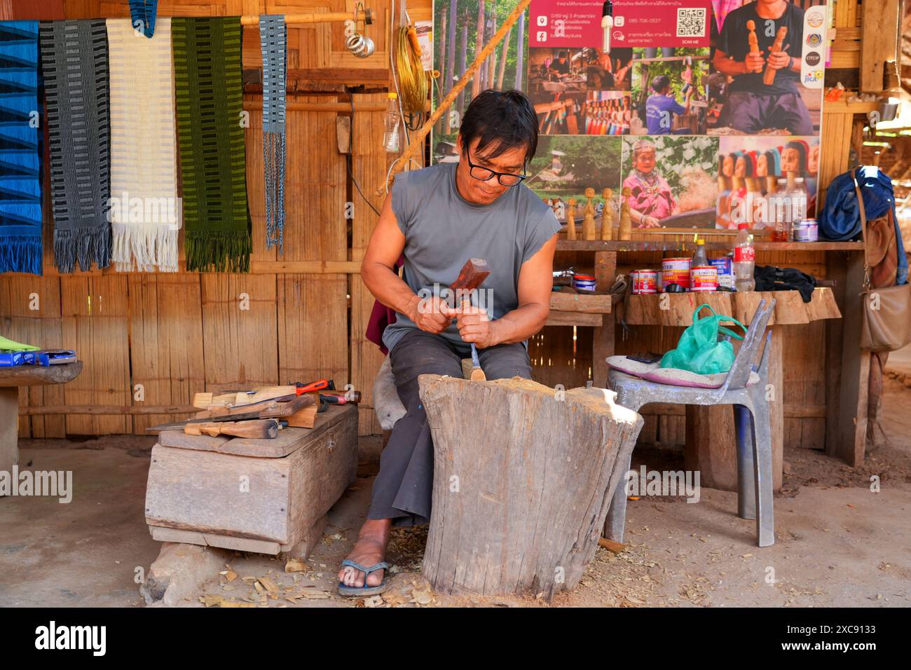 Kayan refugee craftsman chiseling wood to make a small statue in the ...
