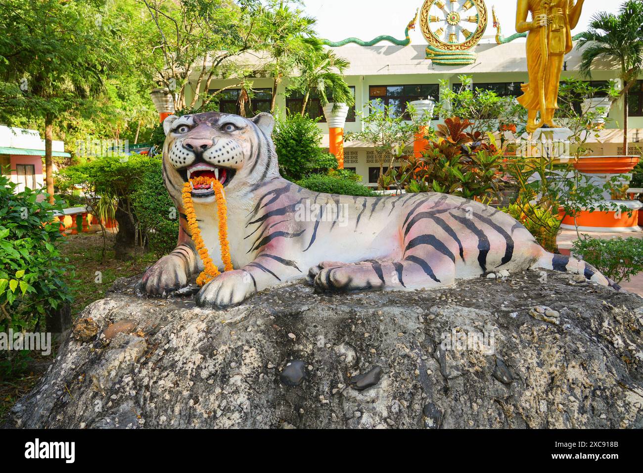 Statue of a sacred tiger holding a flower necklace in its mouth in the ...