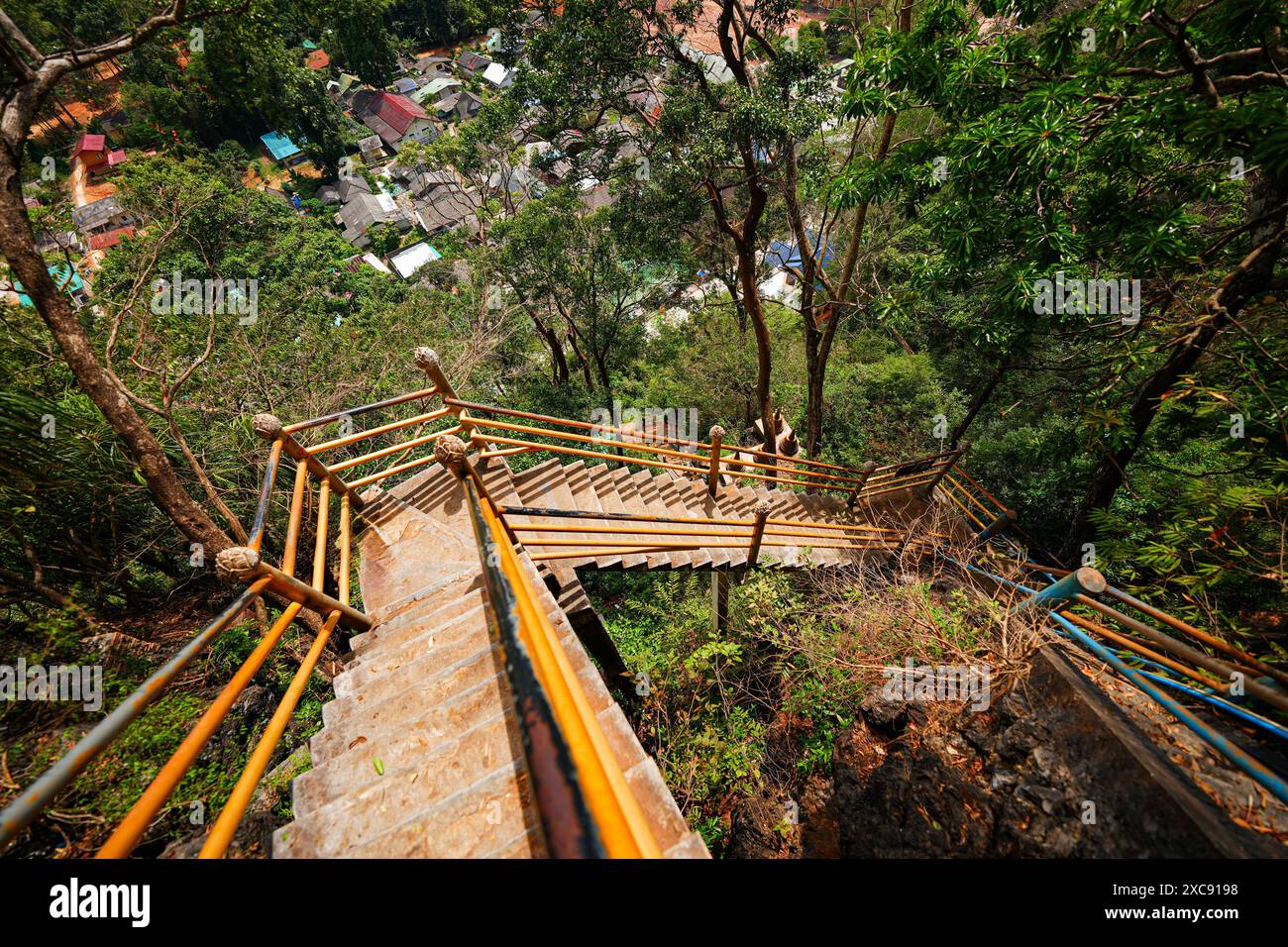 Steep stairs climbing up a limestone karst cliff through the rainforest ...