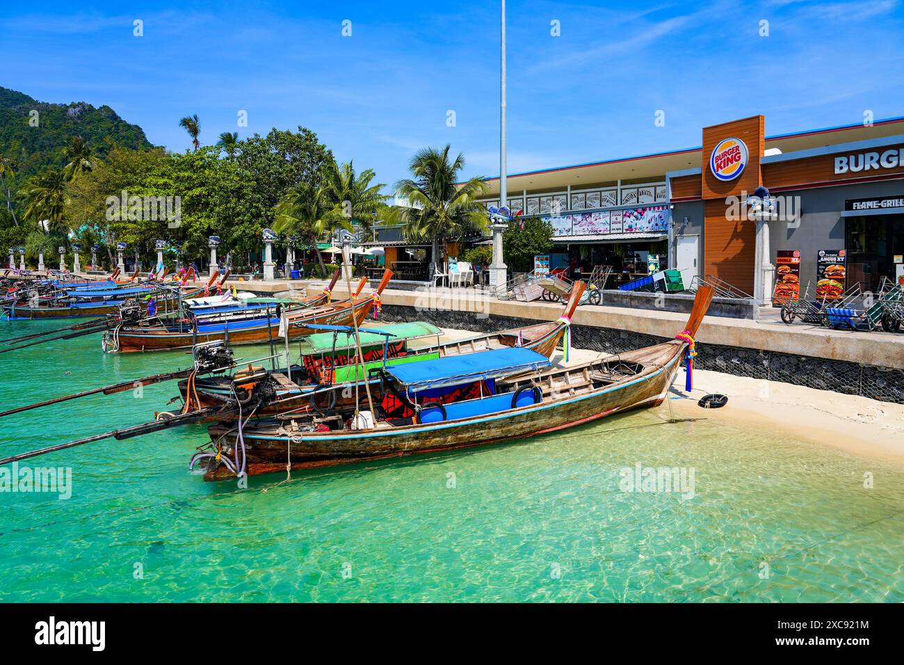Koh Phi Phi, Thailand - February 8, 2023 : Longtail boats moored in front of a beachfront Burger ...