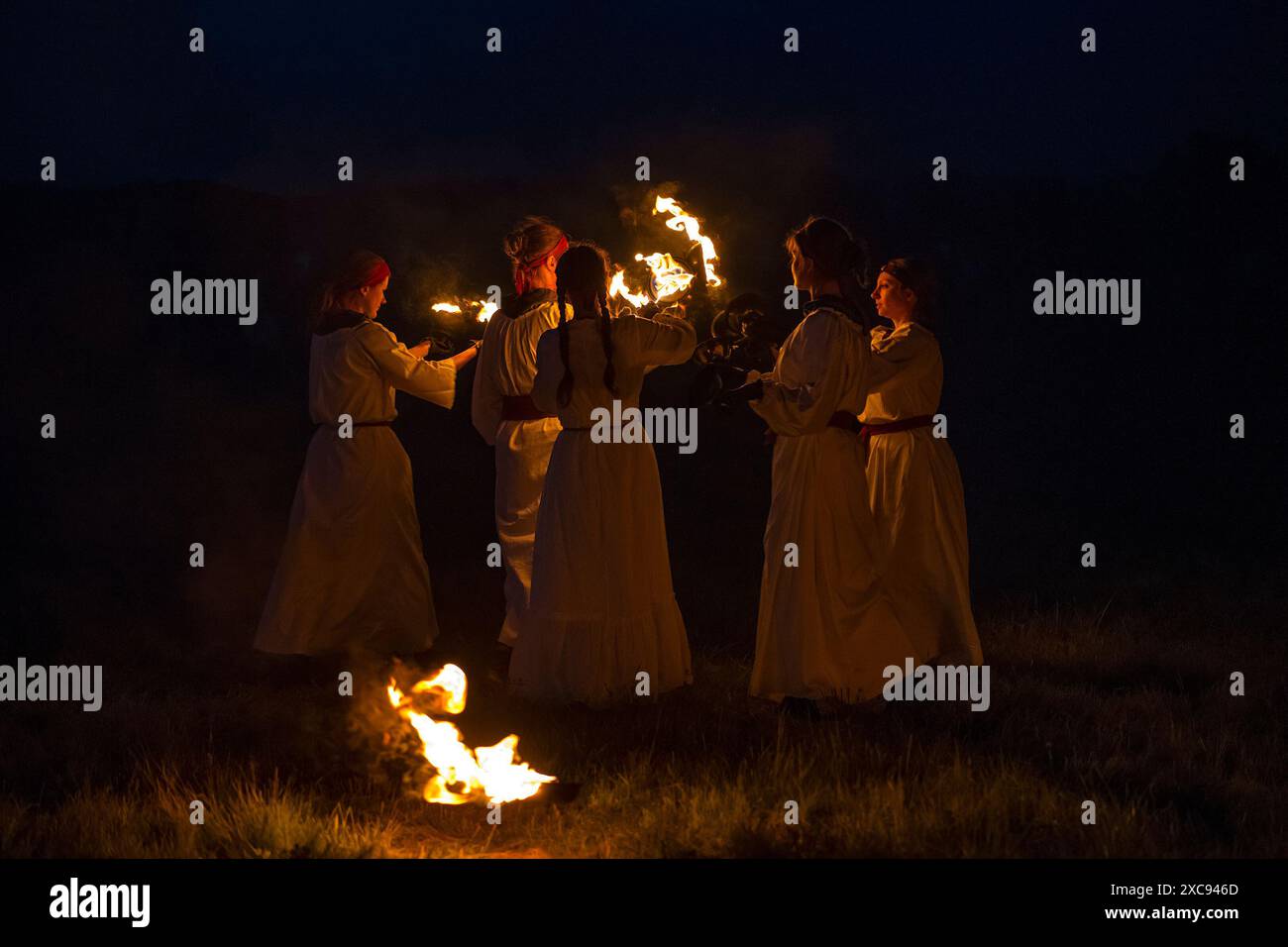 TVER REGION, RUSSIA - JULY 21, 2023: Girls in white dresses light a fire on a dark night ...