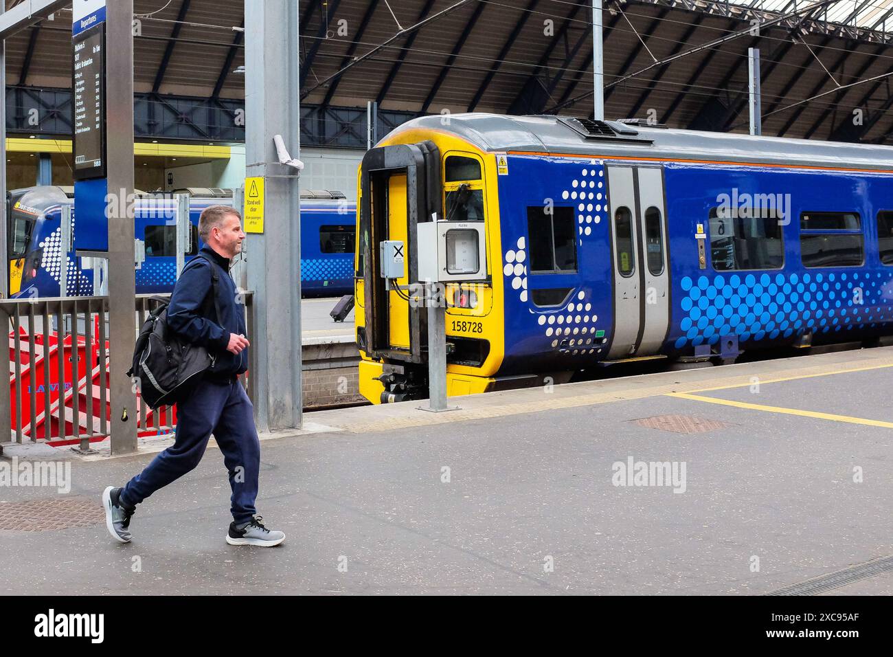 Male passenger walking on the platform passed the Scotrail owned class ...