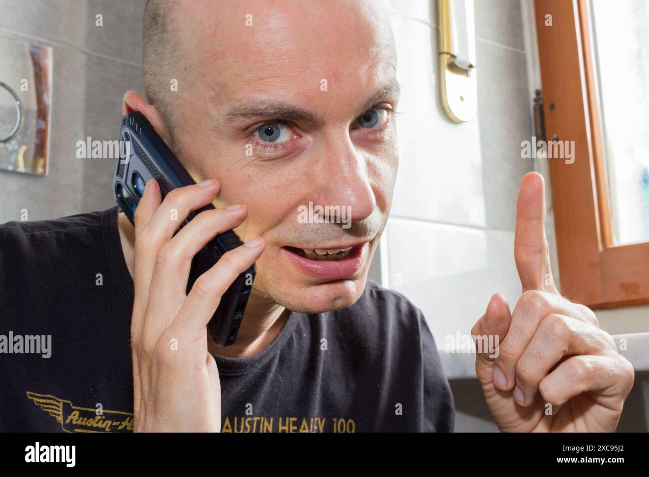 White man talking at the phone while in the bathroom in the daytime ...