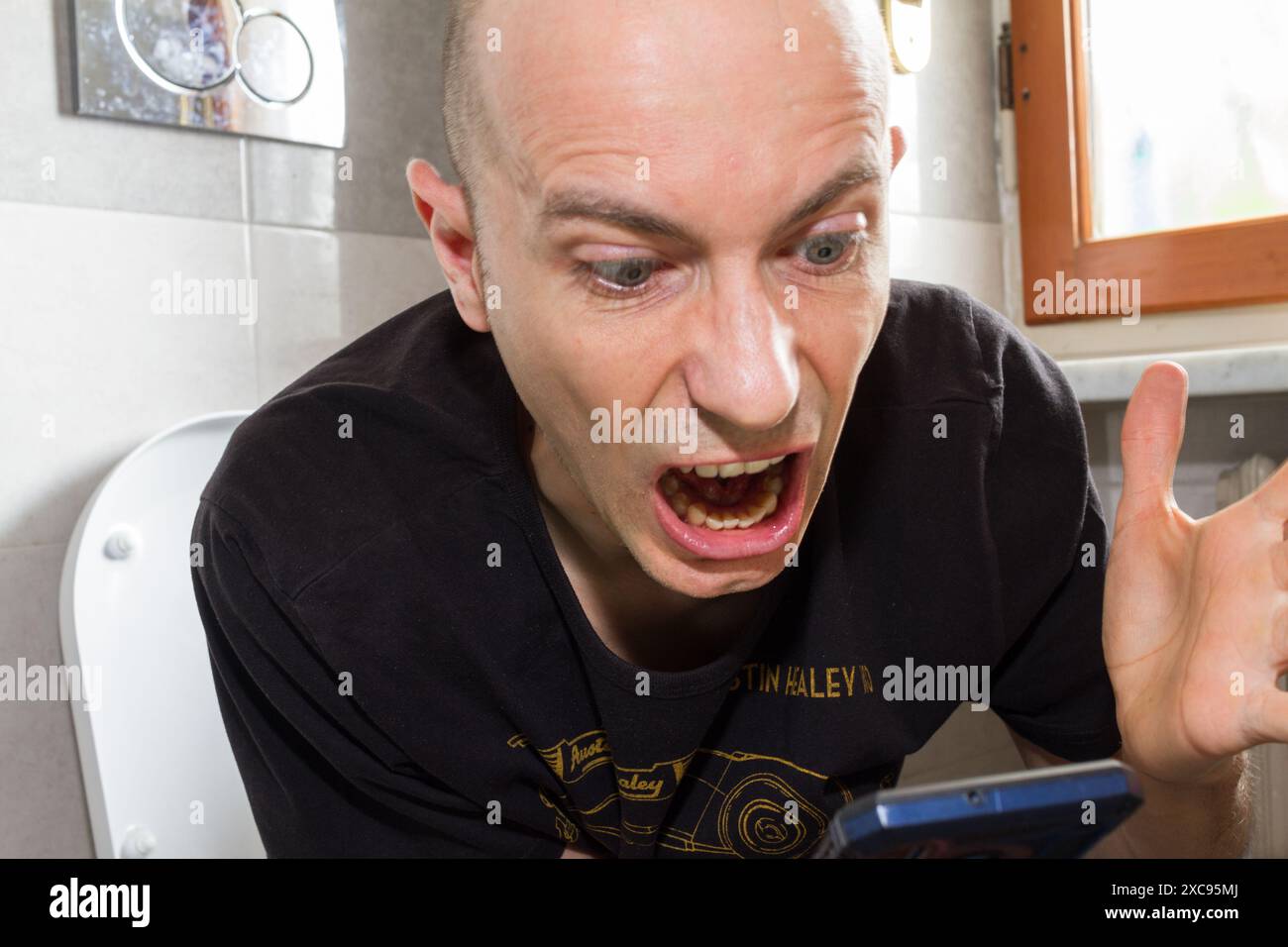 White man talking at the phone while in the bathroom in the daytime ...