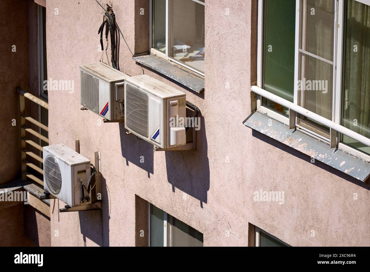 Old air conditioning heat pump outdoor unit against rose wall ...