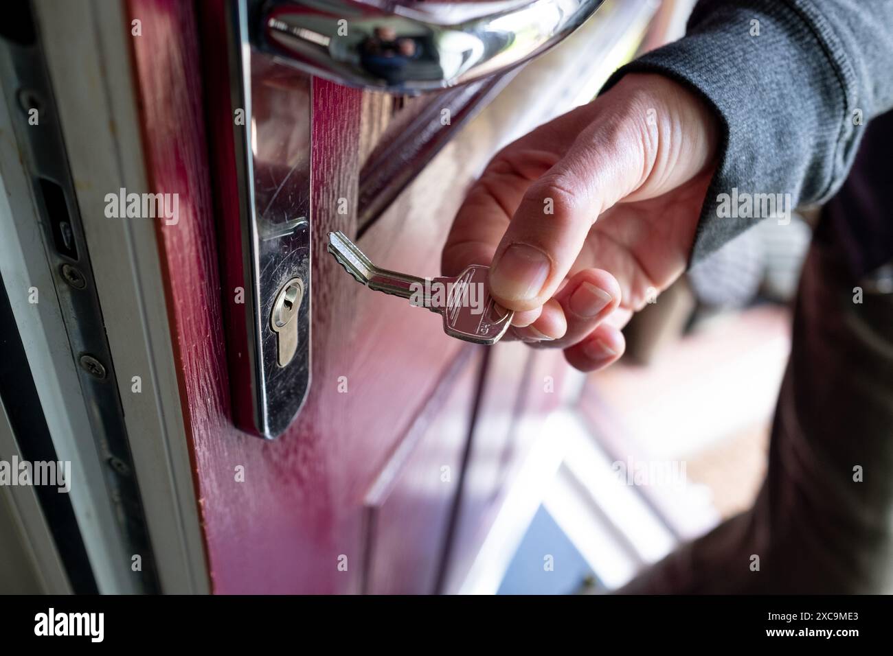 A bent key held in the hand next to a front door lock after becoming ...