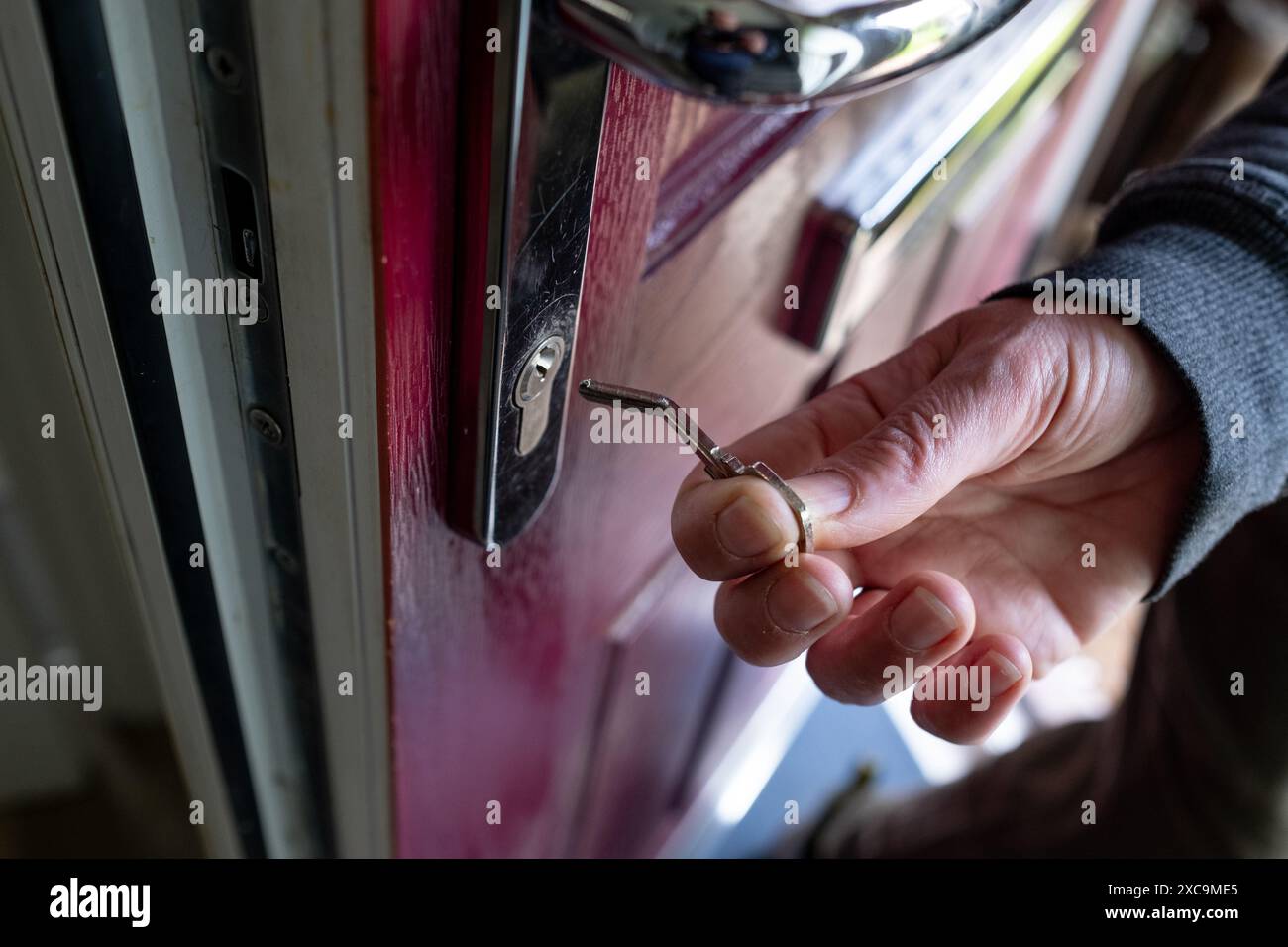 A bent key held in the hand next to a front door lock after becoming ...