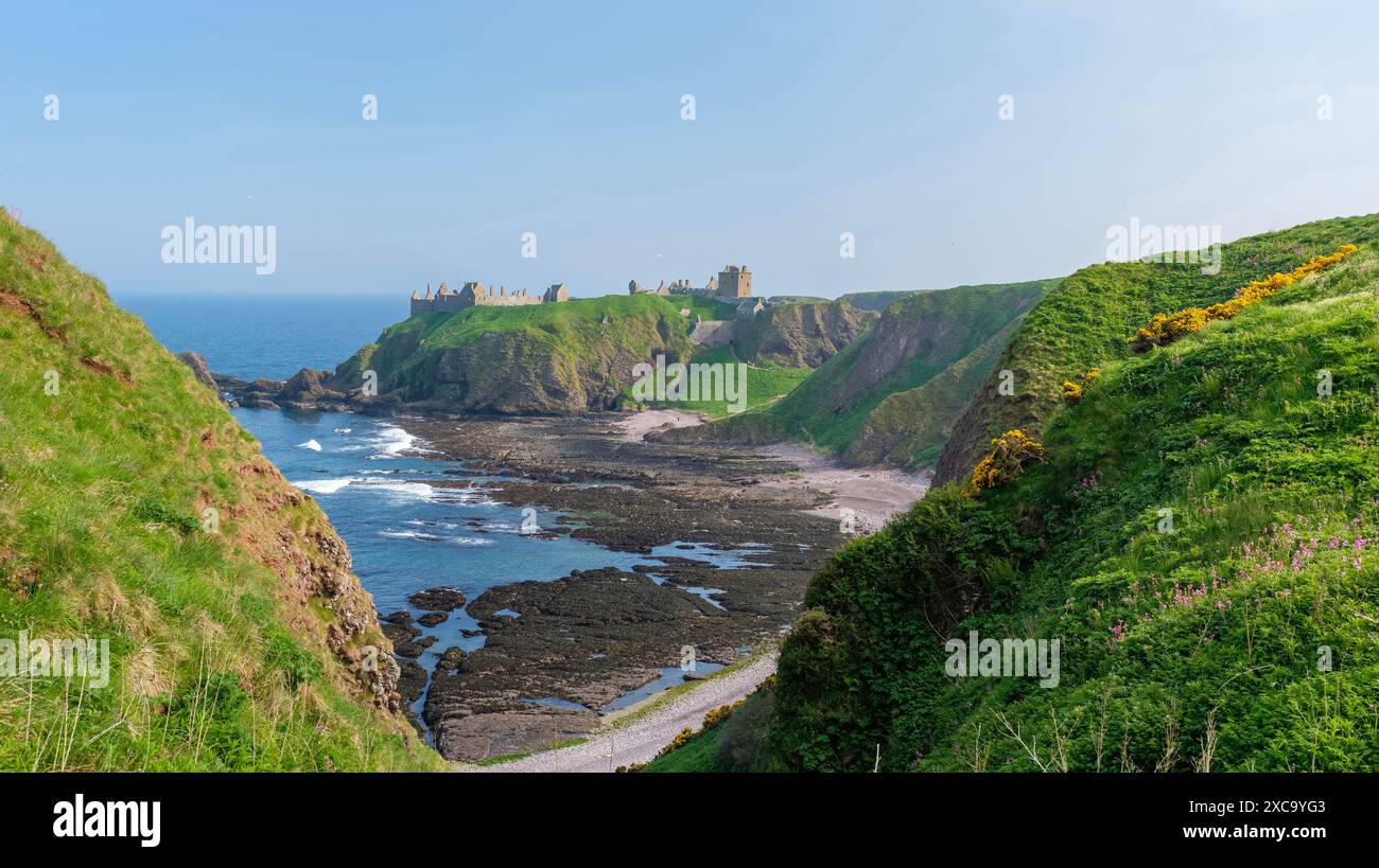 view of the Dunnottar Castle perched on the cliff above a coastal walk ...
