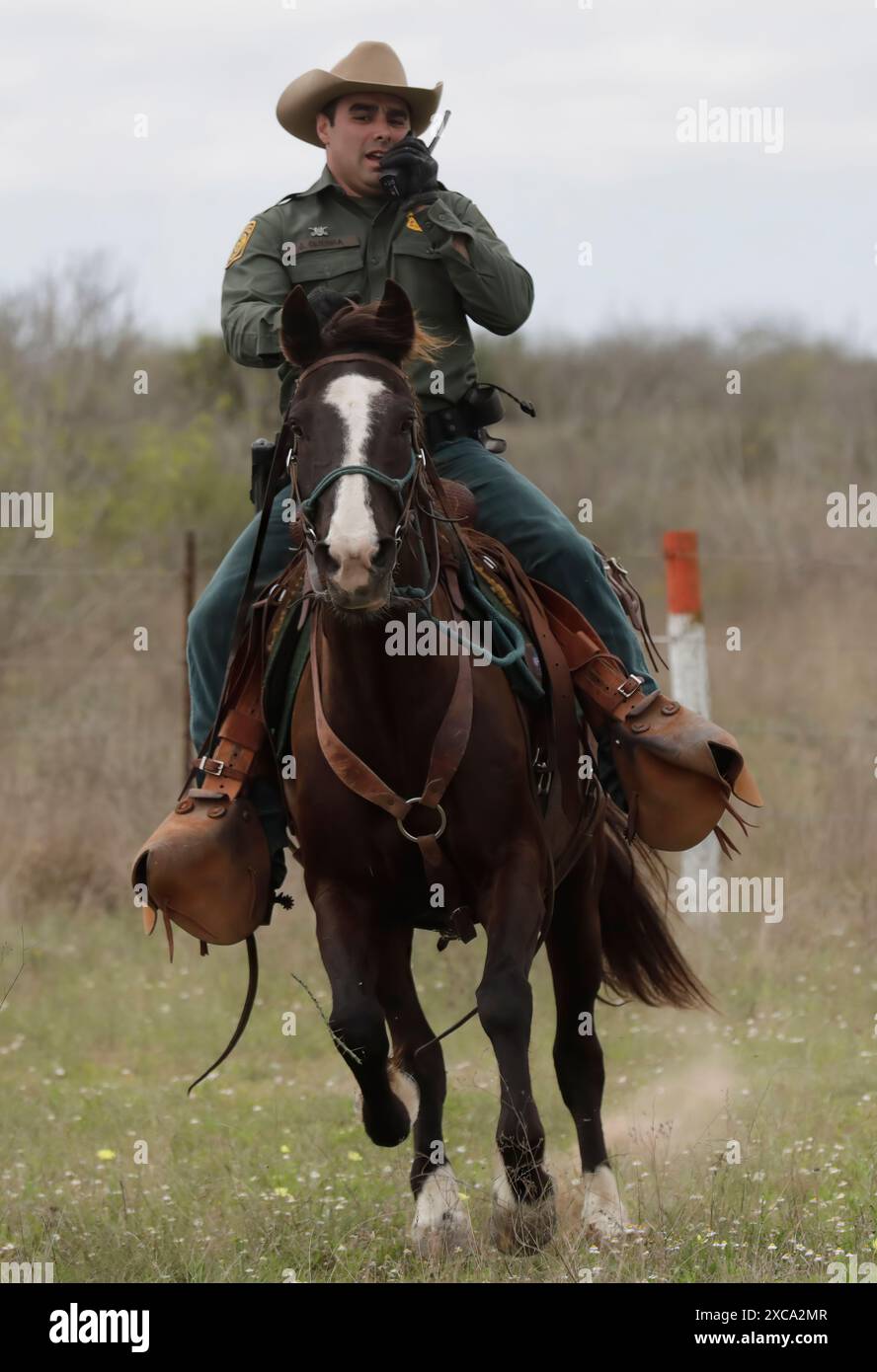 A horse-mounted U.S. Border Patrol agent communicates with cohorts by ...