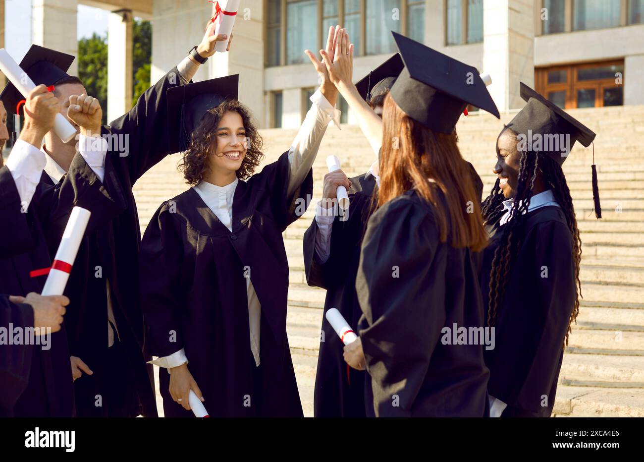 Happy smiling graduate students giving high five to each other ...