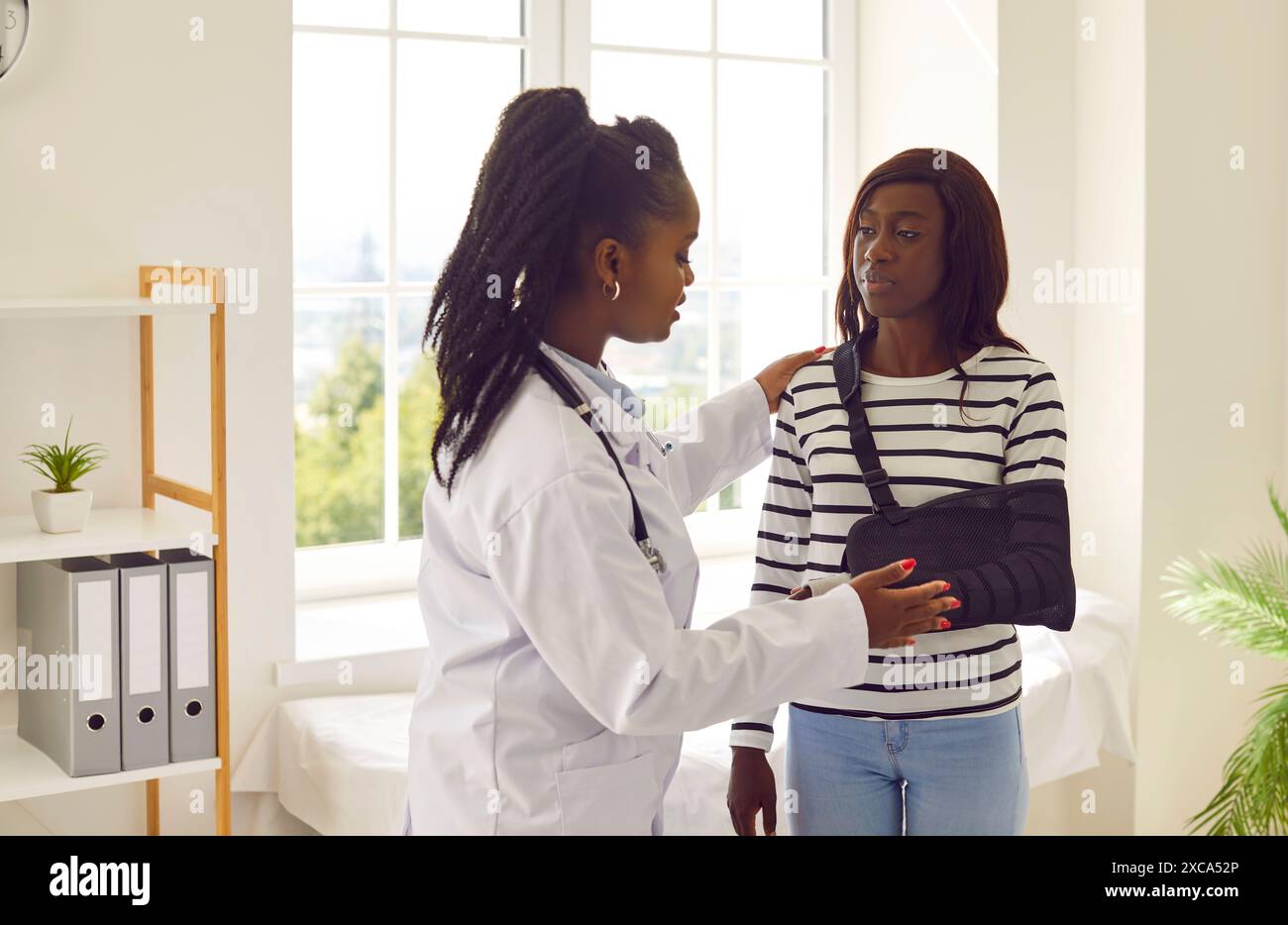 Doctor supporting female patient with broken arm and giving her ...