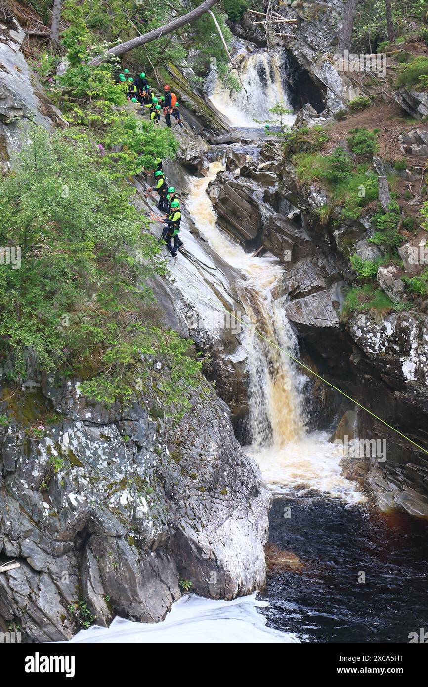 People abseiling down rockface and into a pool under the Falls of Bruar ...