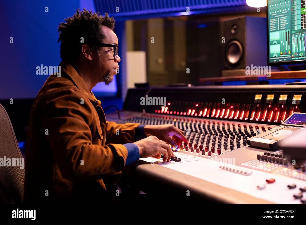 African american sound designer uses control desk with automatic ...