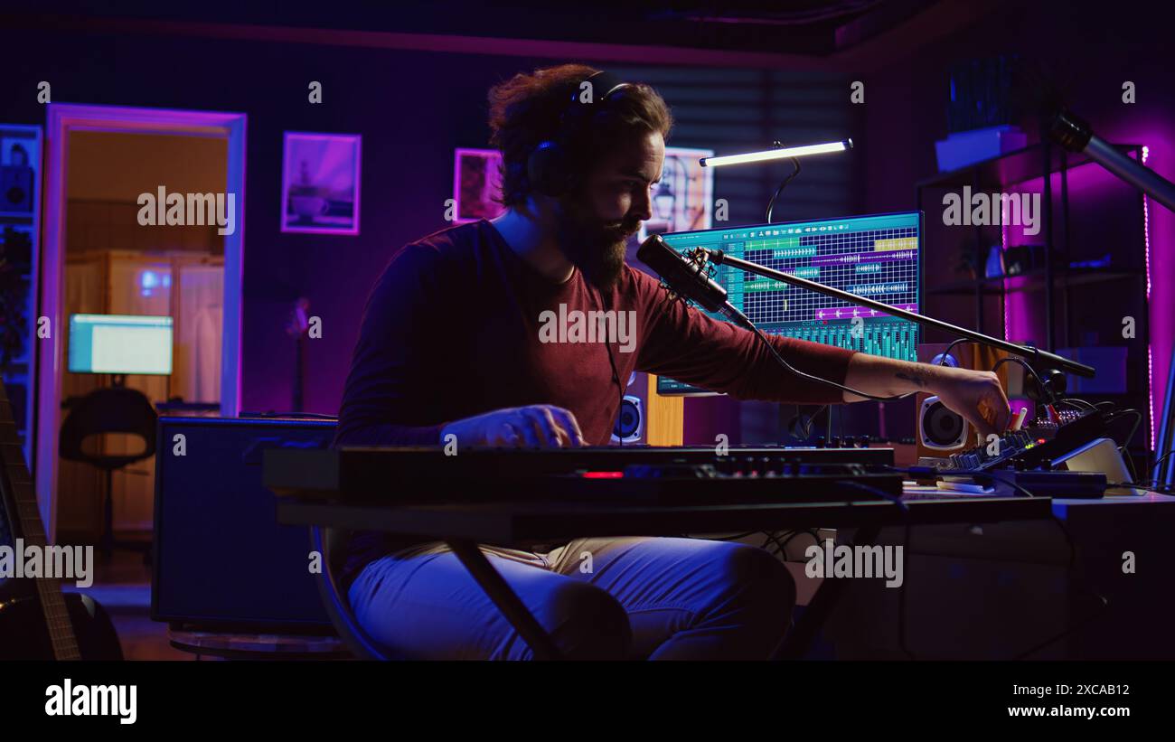 Sound engineer pressing keys of electric synthesizer and recording new ...