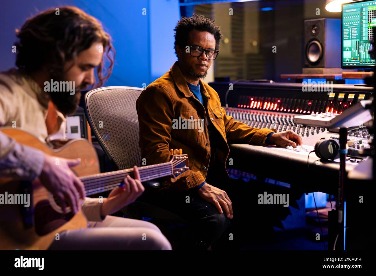 Singer recording electro acoustic guitar in professional music studio ...