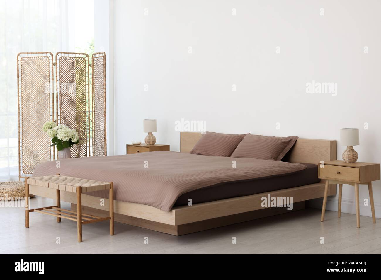 Folding screen, comfortable bed, ottoman and bedside tables in room ...