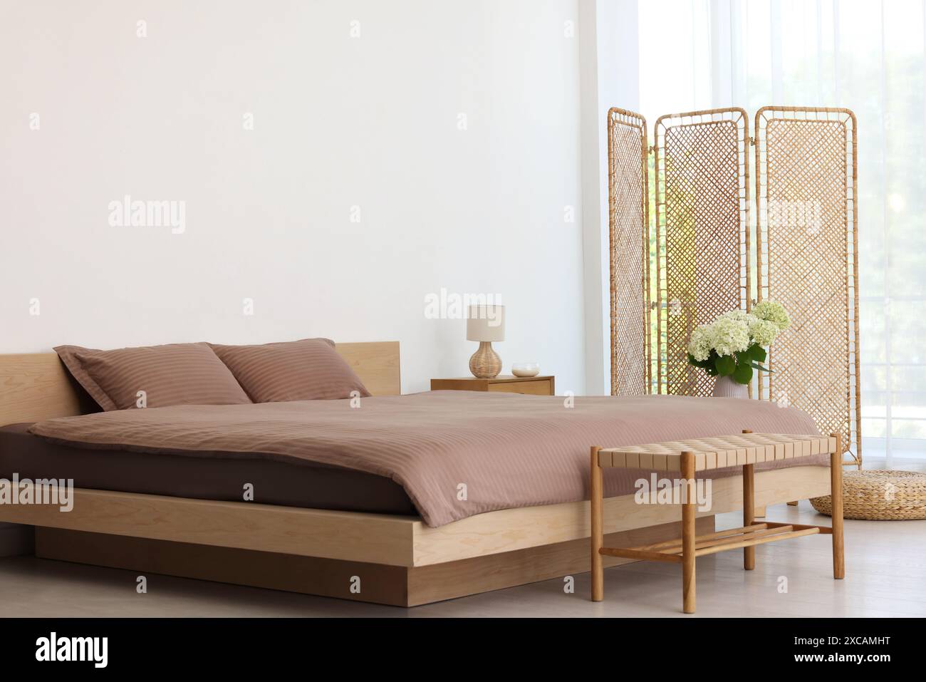 Folding screen, comfortable bed, ottoman and bedside table in room ...