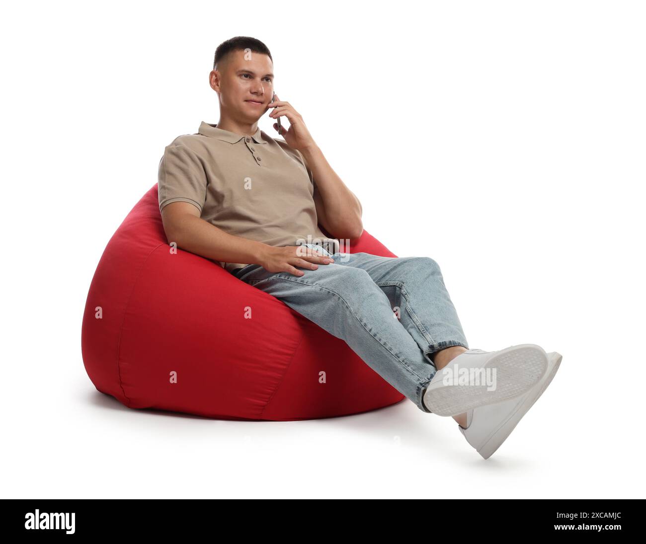 Handsome man talking by smartphone on red bean bag chair against white ...