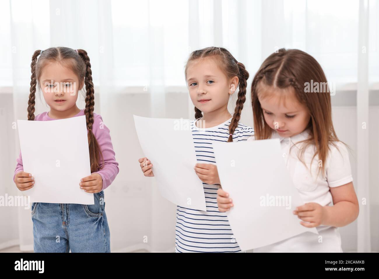 Cute little children with sheets of paper singing indoors Stock Photo ...