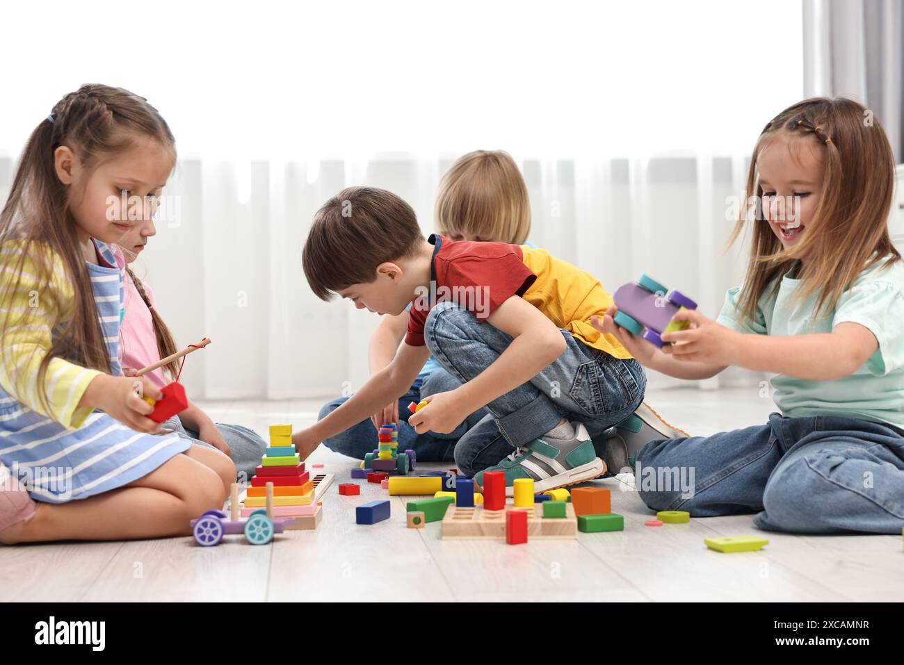 Group of children playing together on floor indoors Stock Photo - Alamy