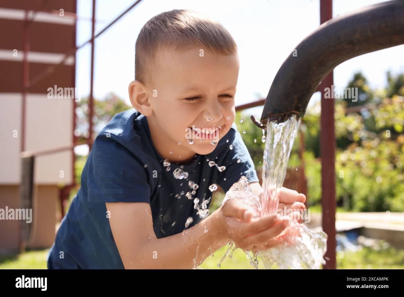Water scarcity. Cute little boy drawing water with hands from tap ...